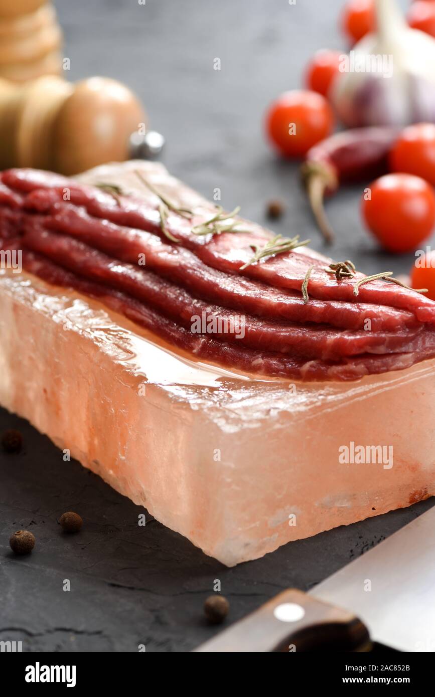 Cooking meat on pink salt block concept. Raw Black Angus beef marinated ...