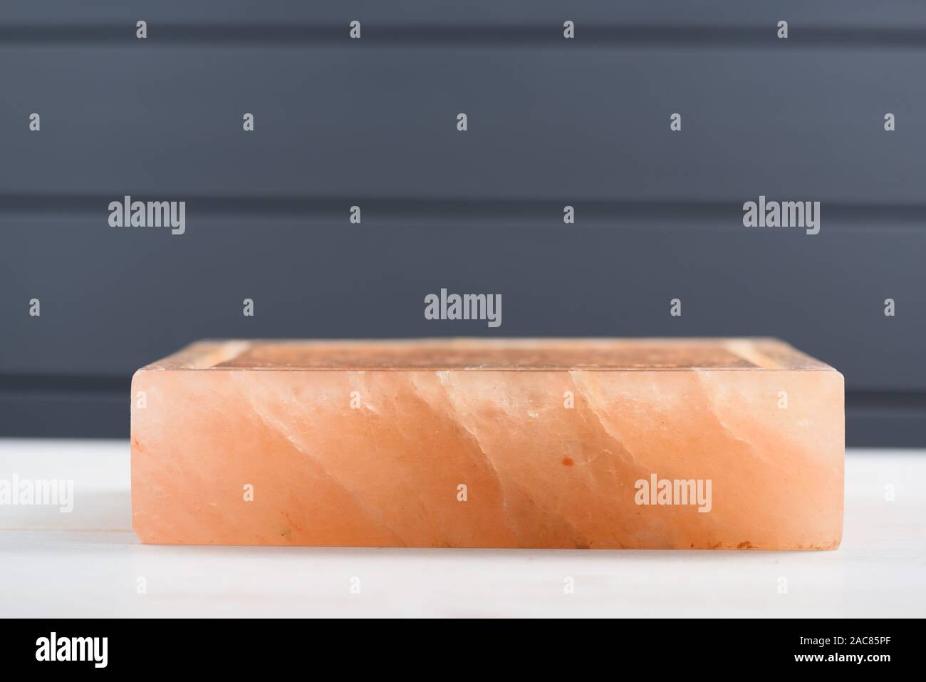 Hymalayan pink salt block with cracks on dark grey background side view ...