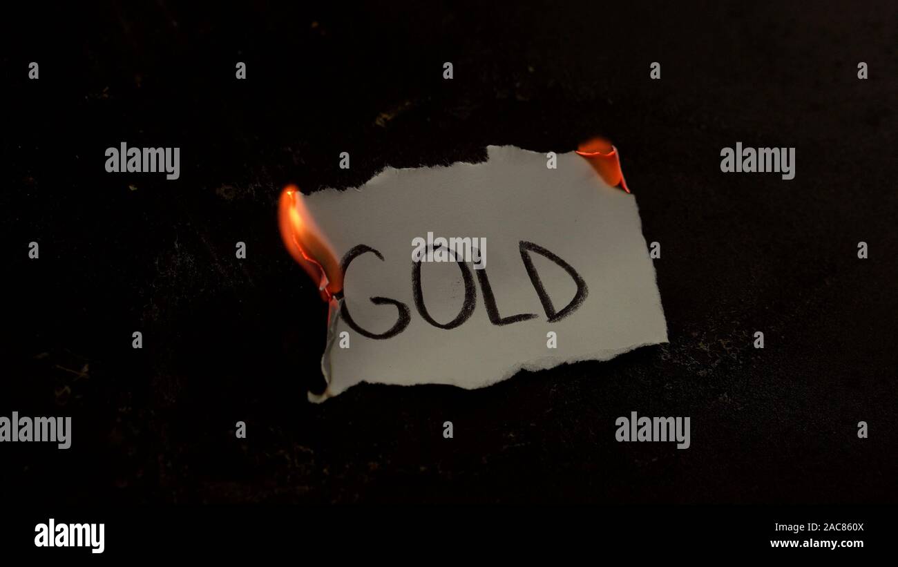 Gold word written on white paper burns. Fire with smoke and ashes on ...