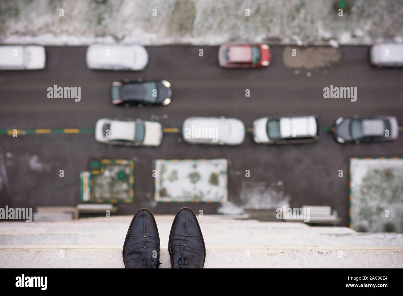 Close-up of man's feet standing on the edge of the roof. Top view on ...