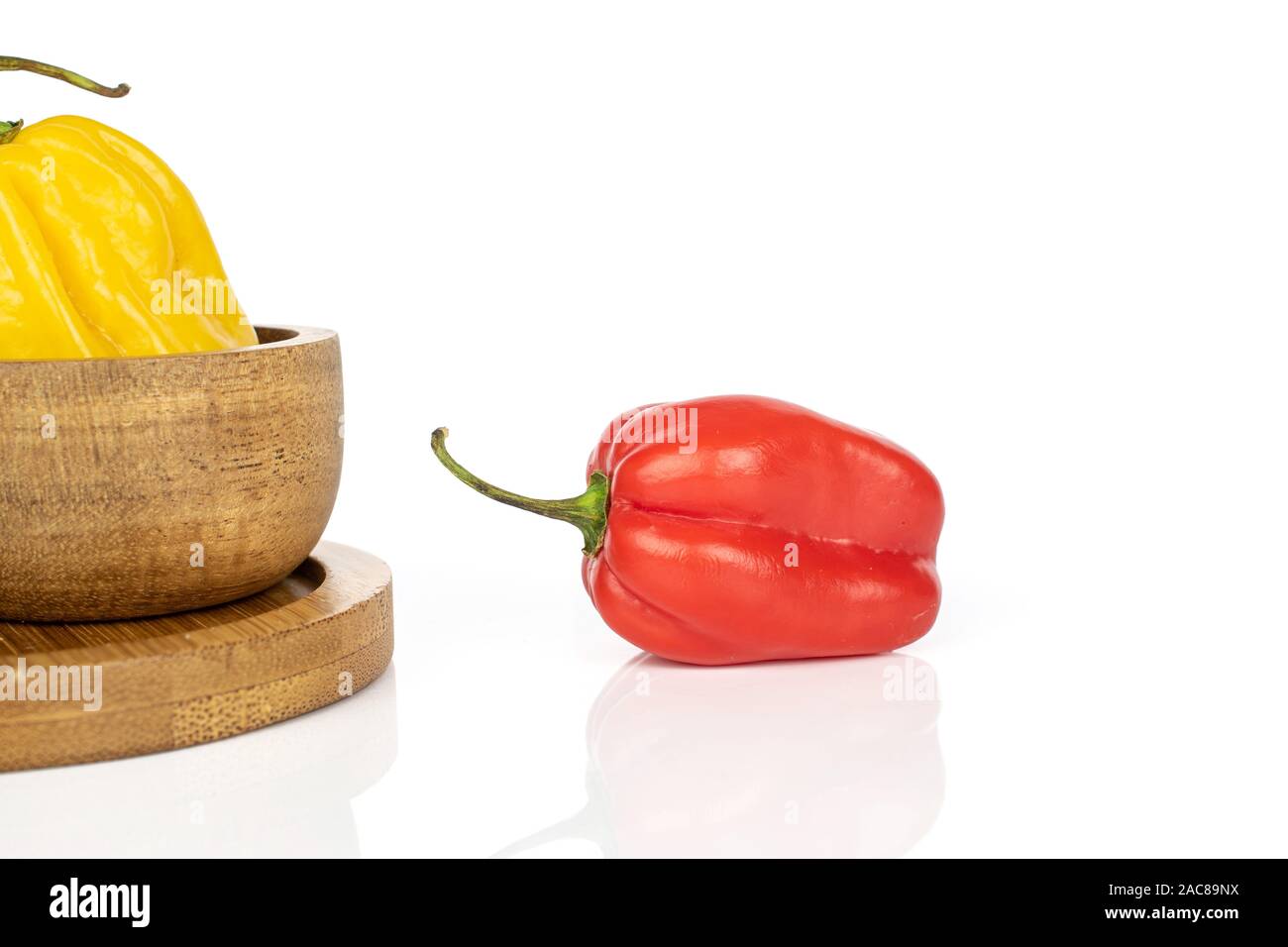 Group of two whole hot chili habanero on round bamboo coaster in bamboo ...