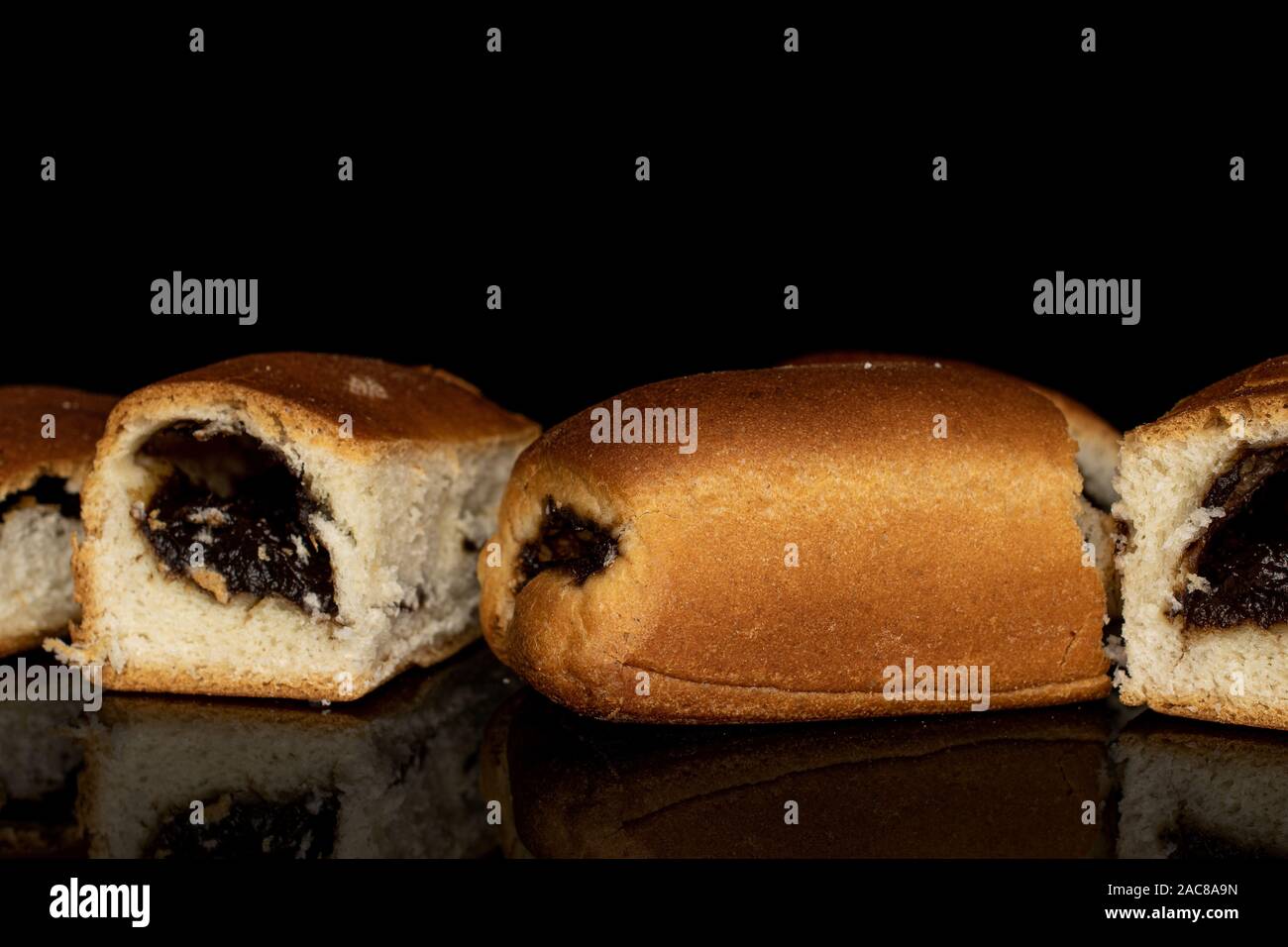 Group of four whole disordered sweet czech bun isolated on black glass ...