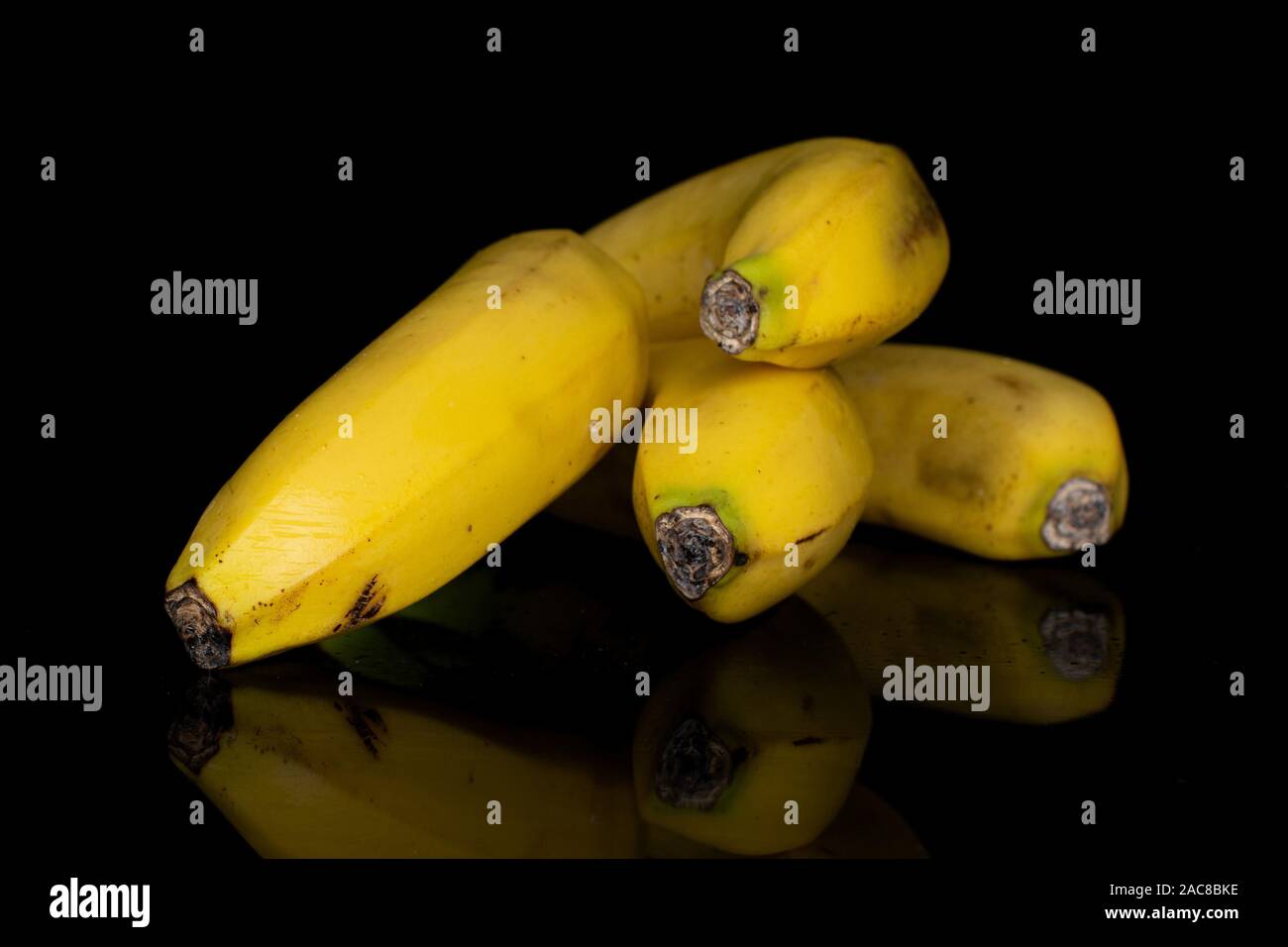 Group of four whole sweet yellow banana isolated on black glass Stock ...
