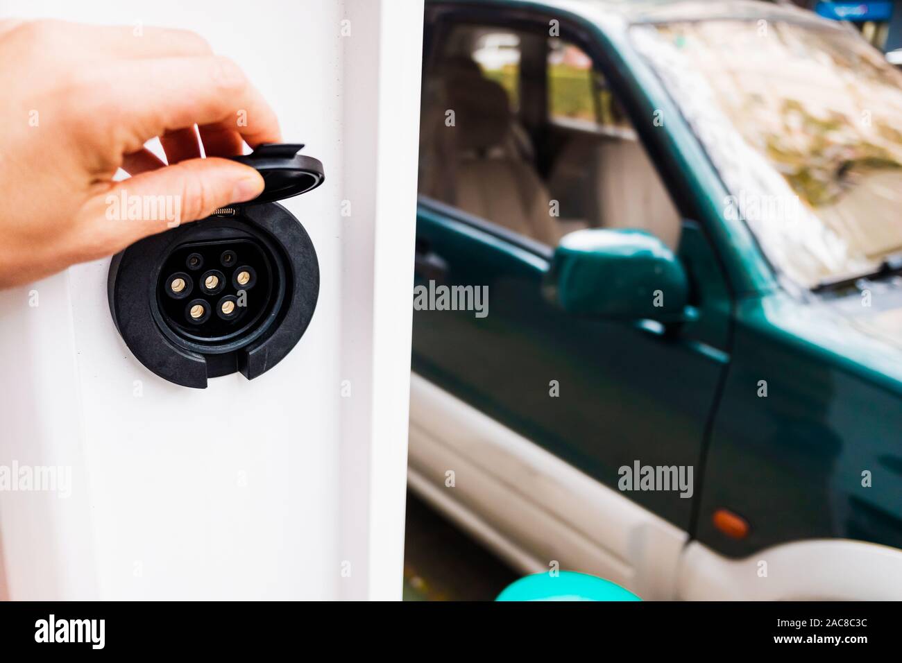 A man prepares the plug on an electric car charging pole Stock Photo ...