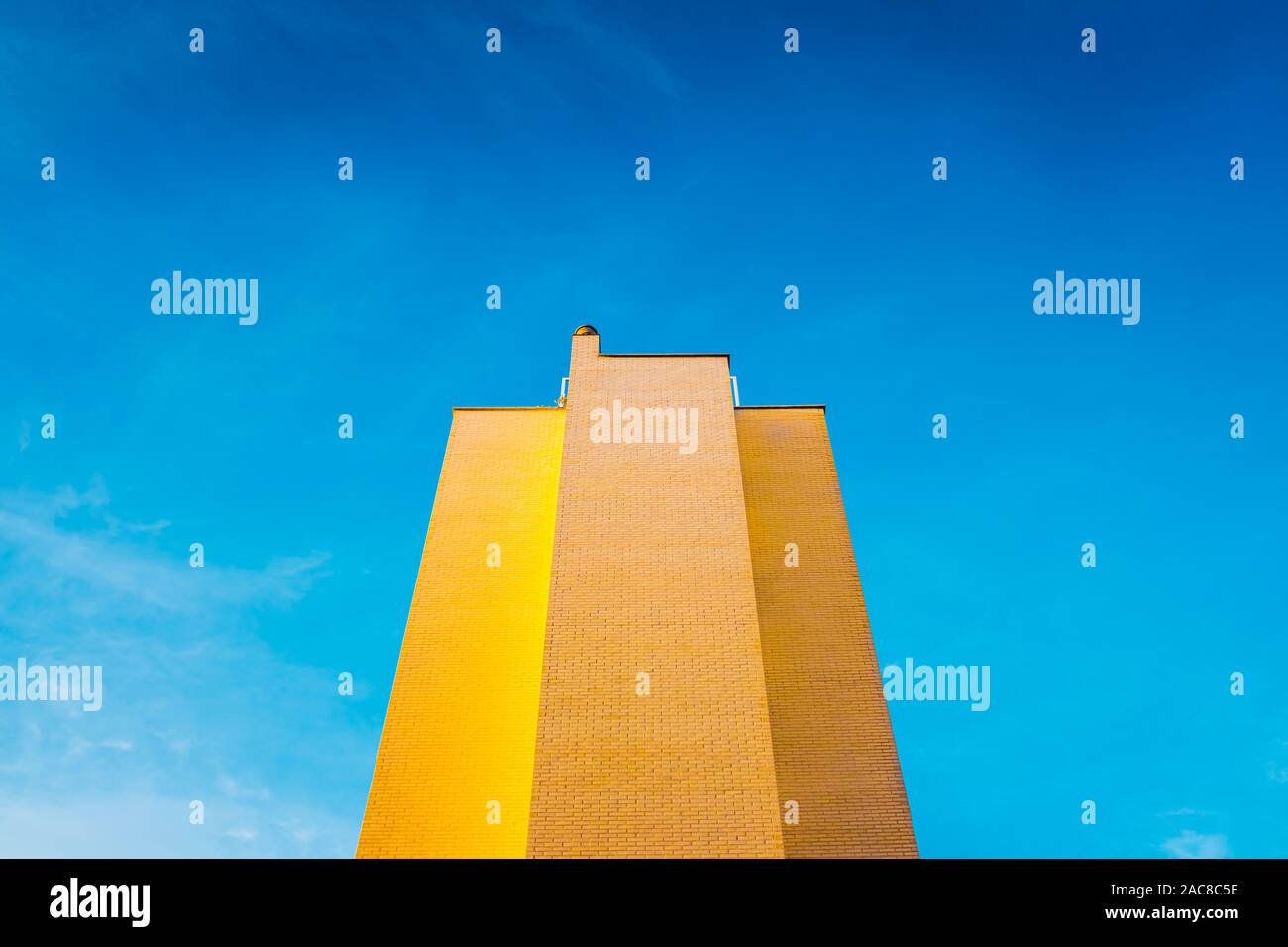 High brick building, warm and yellow at sunset, with the background of ...