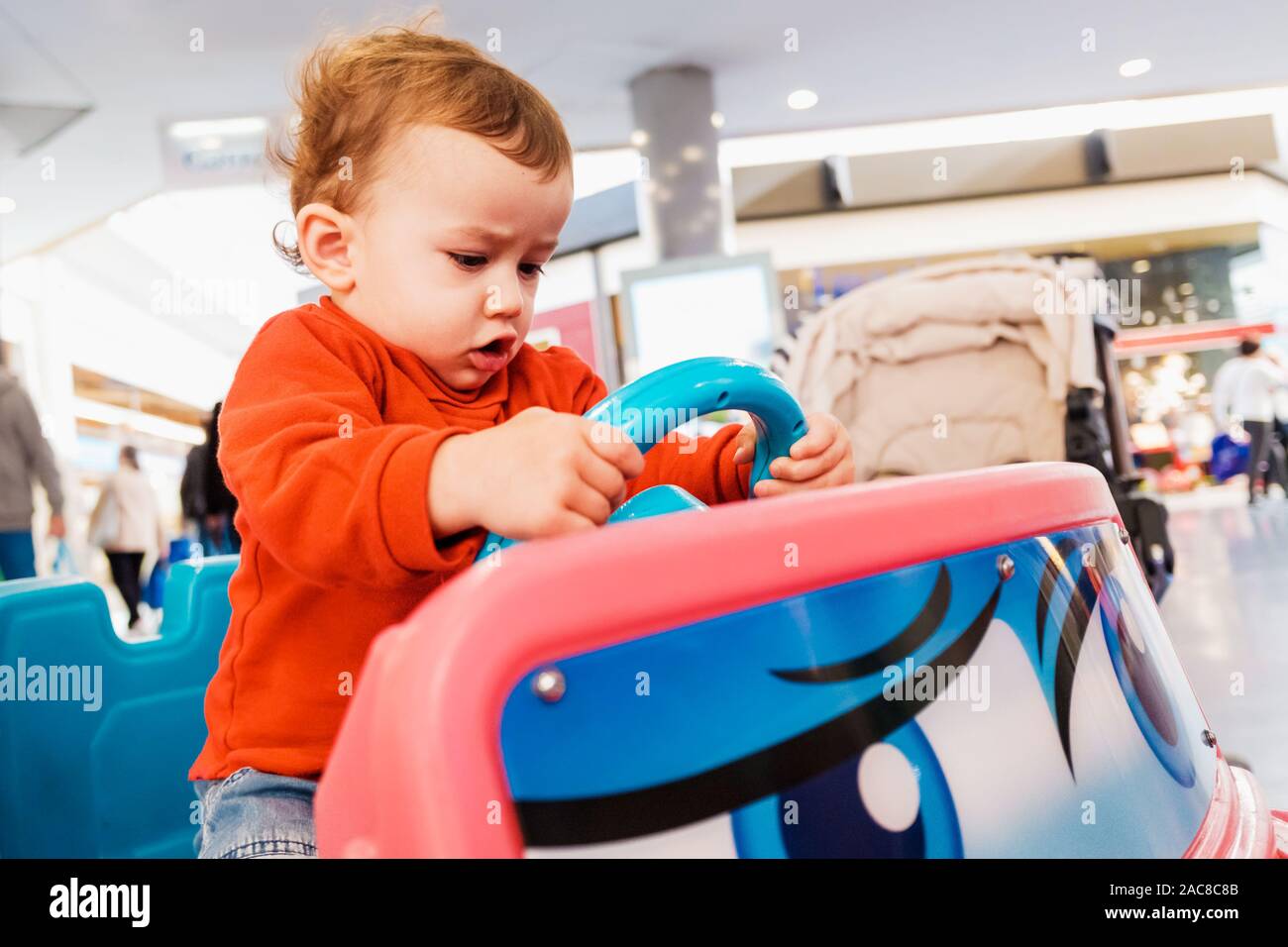 1 year old baby play in amusement rides car inside a mall while his ...