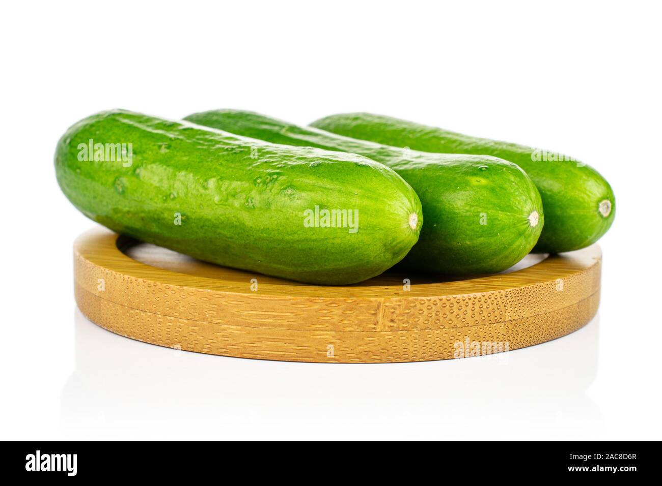Group of three whole fresh green baby cucumber on bamboo coaster ...