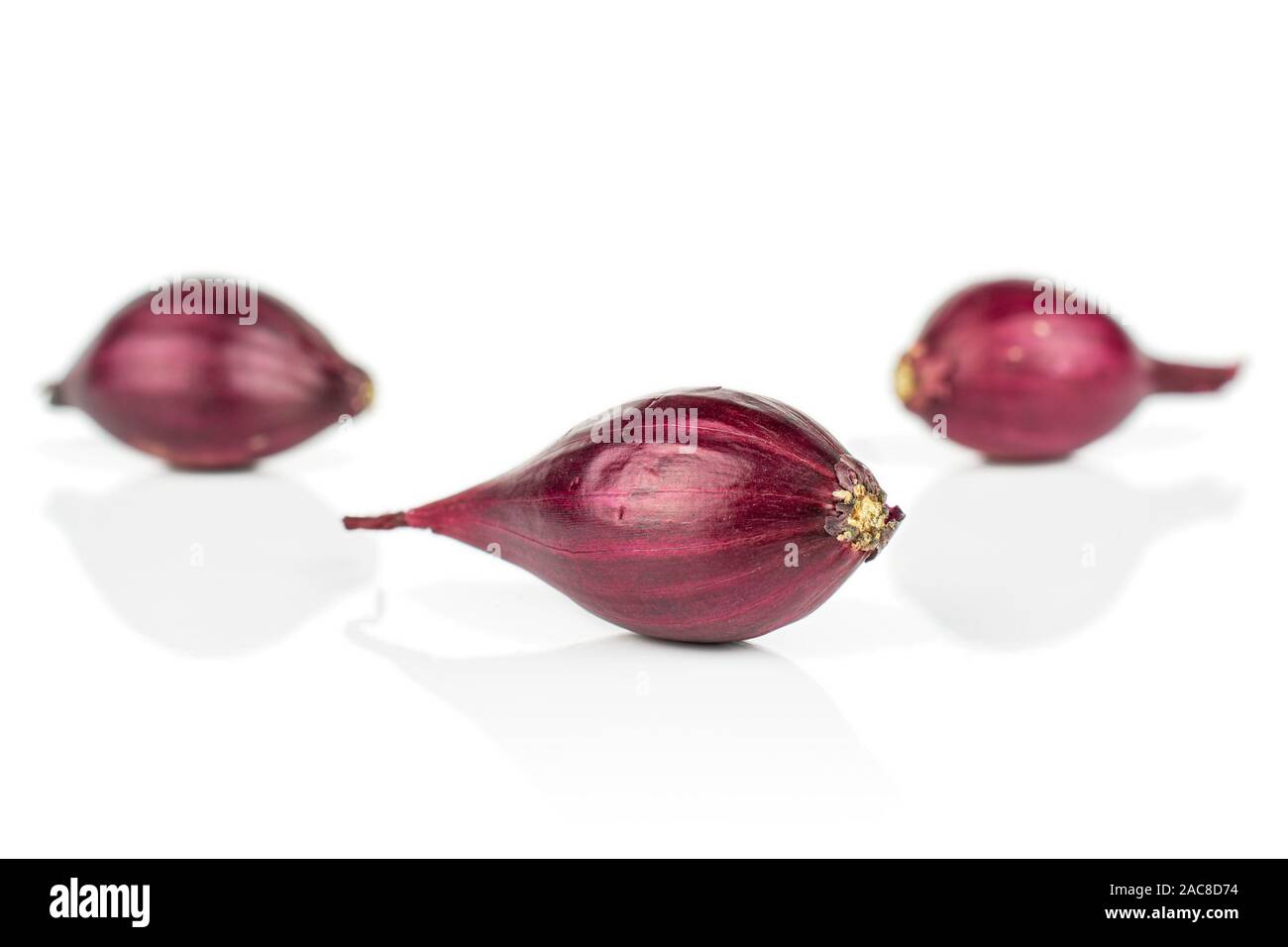 Group of three whole small red onion bulb isolated on white background ...