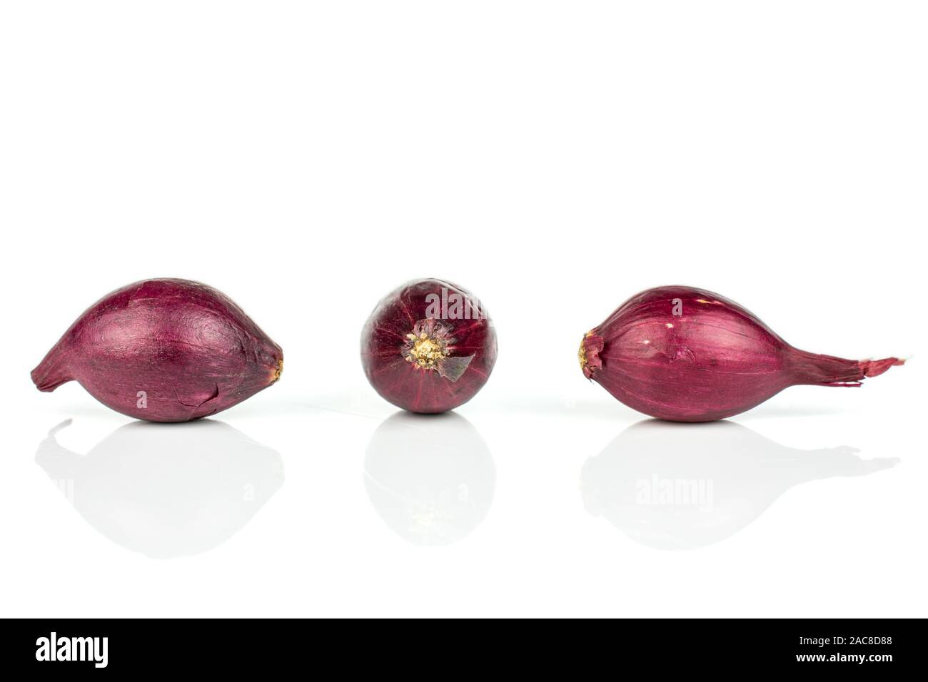 Group of three whole small red onion bulb isolated on white background ...