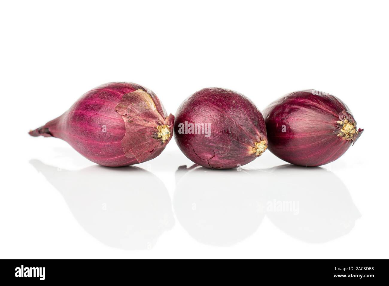 Group of three whole small red onion bulb in row isolated on white ...