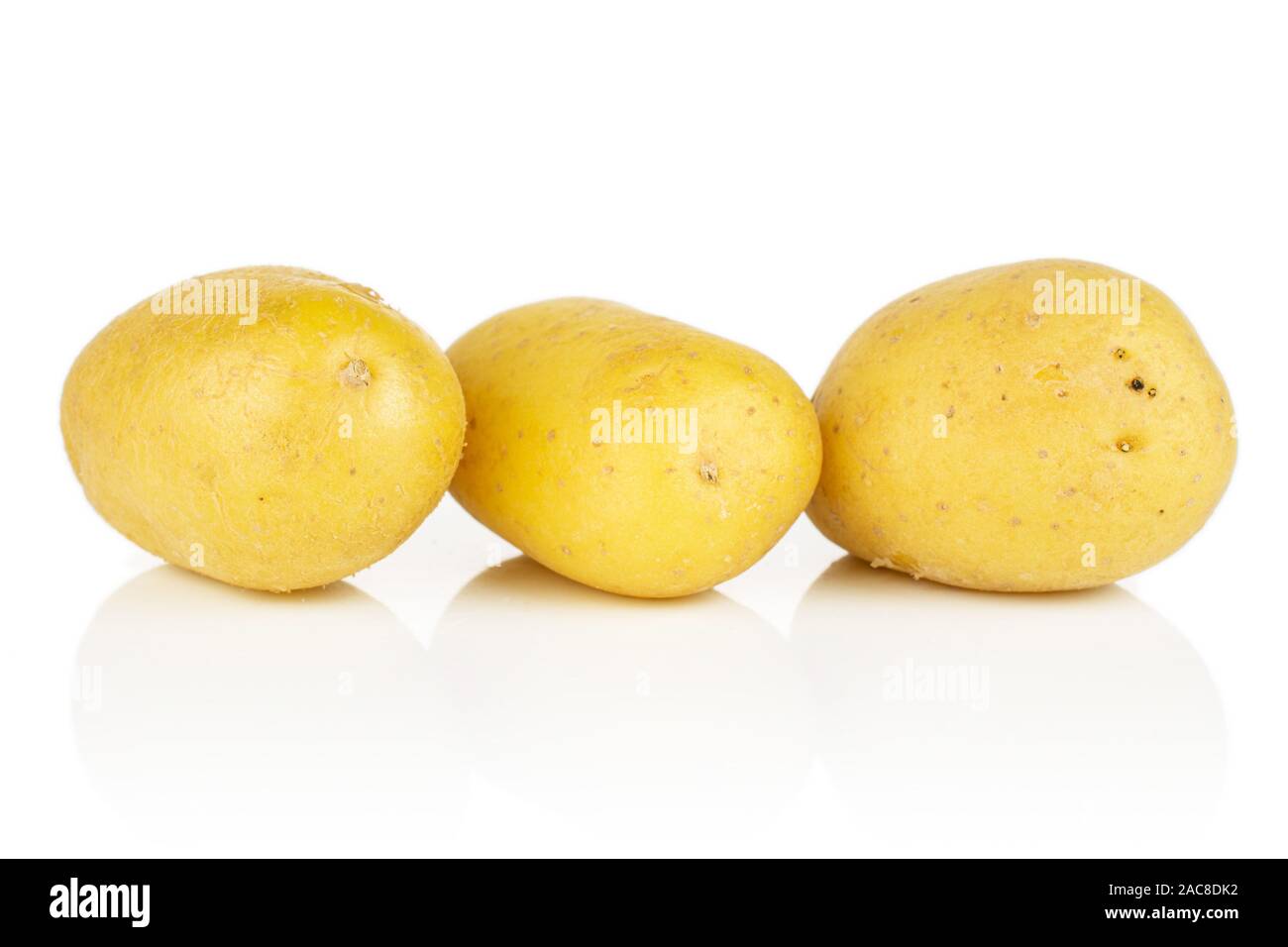 Group of three whole pale yellow potato in row isolated on white ...