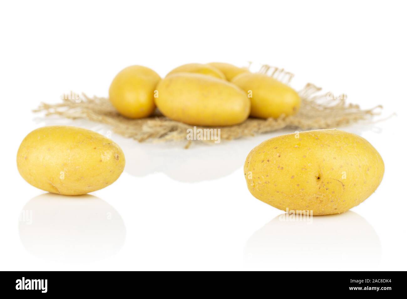 Group of seven whole pale yellow potato on natural sackcloth isolated ...
