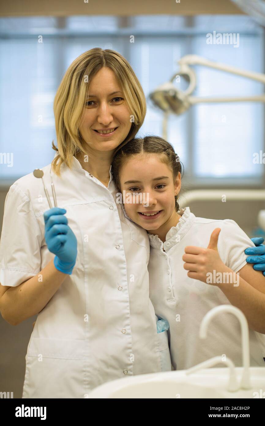 Cute girl patient and woman dentist, together portrait in dental room ...