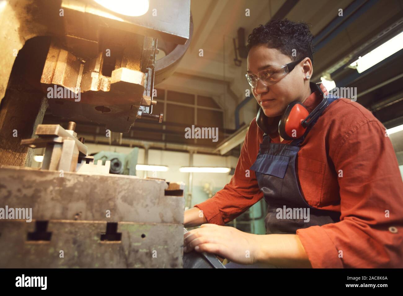 Side view portrait of smiling woman operating industrial machine units ...