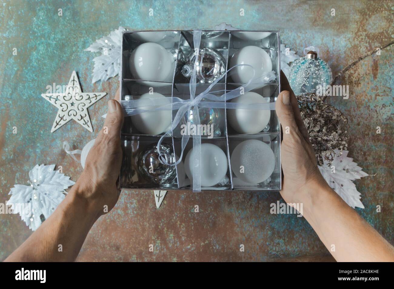 Human hands holding gift box with Christmas balls in white and silver ...