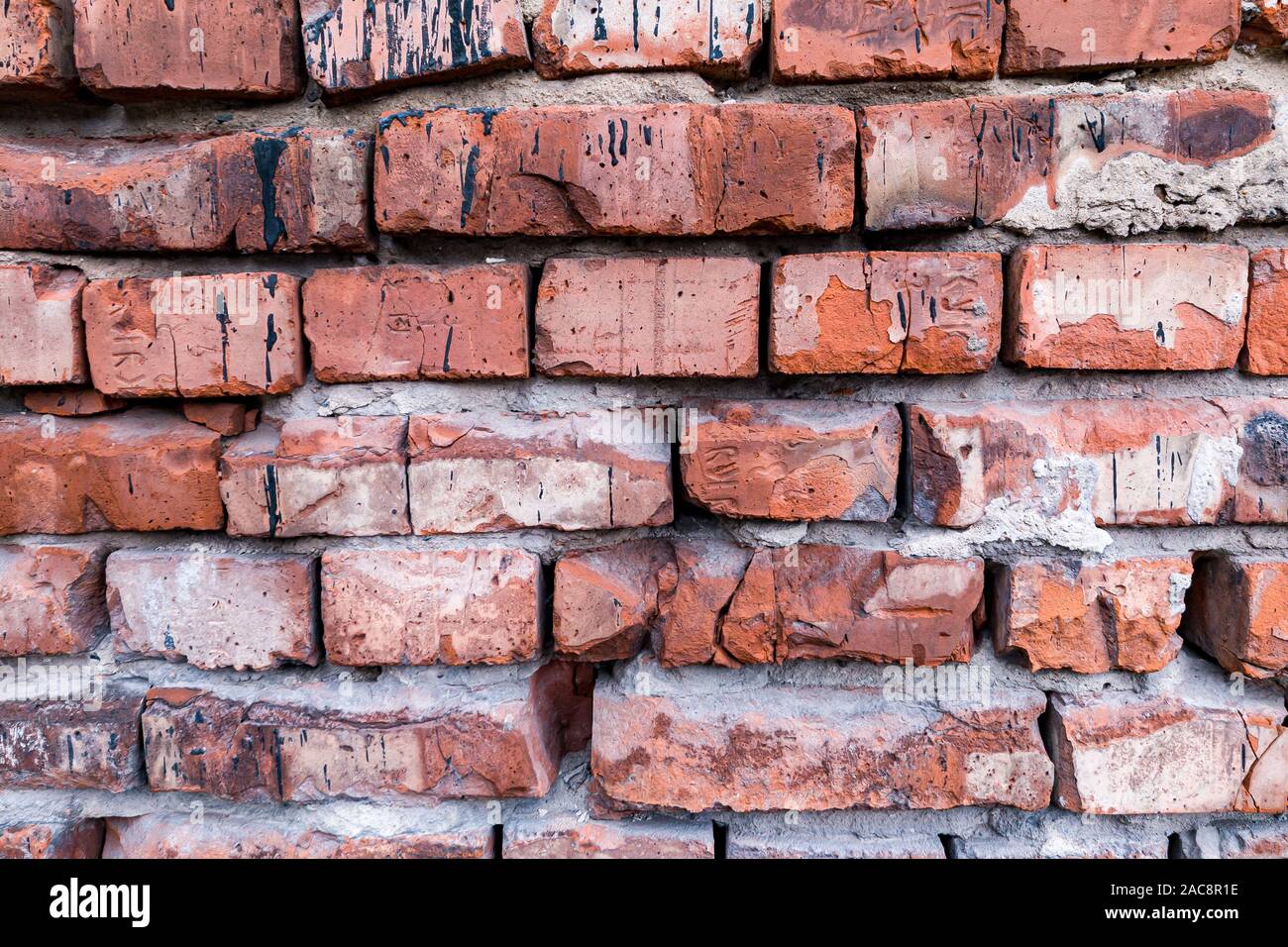 The background is made of red bricks with a wavy relief, cracks, holes ...