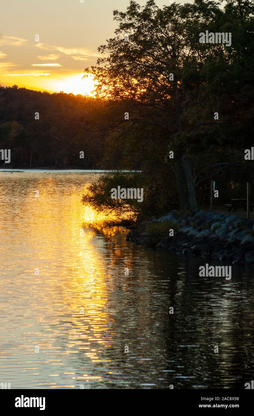 Colorful sunset over Hopkinton Reservoir. Golden sun glowing through a ...