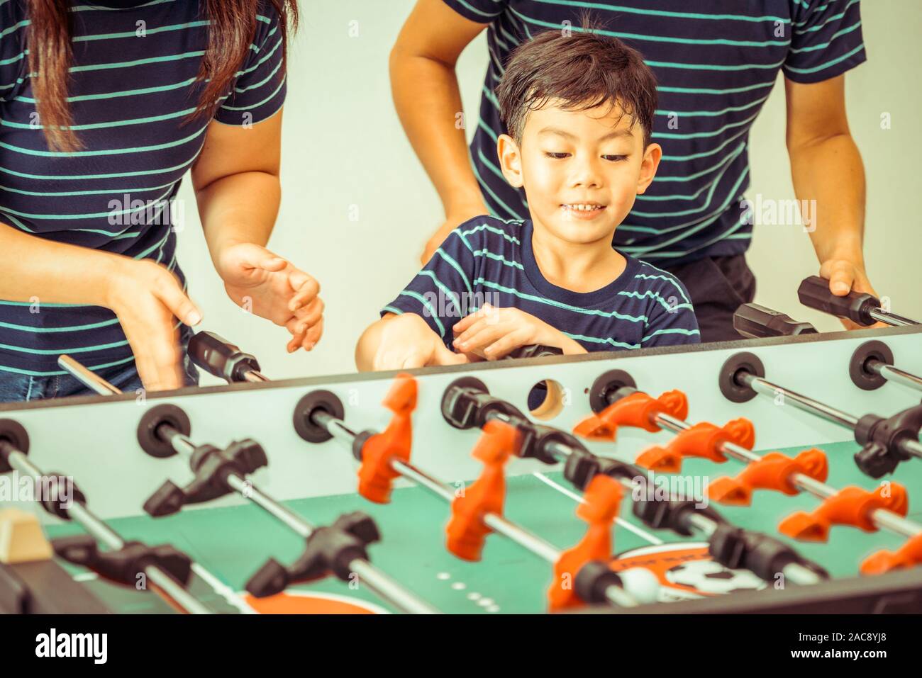 Happy kid playing foosball table soccer with family, father and mother ...