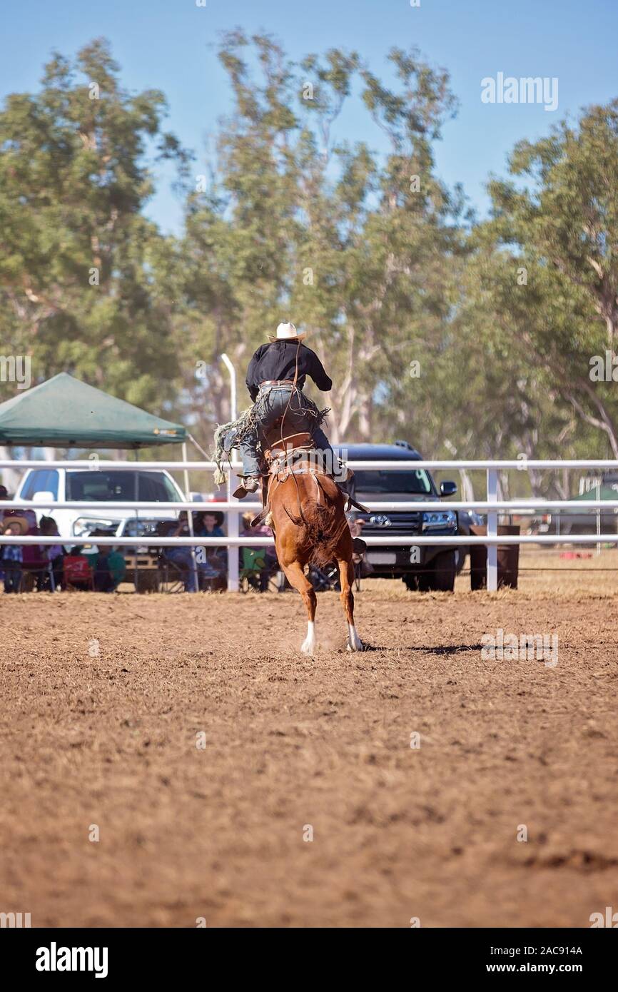 Cowboy riding a bucking bronco horse in a competition at a country ...