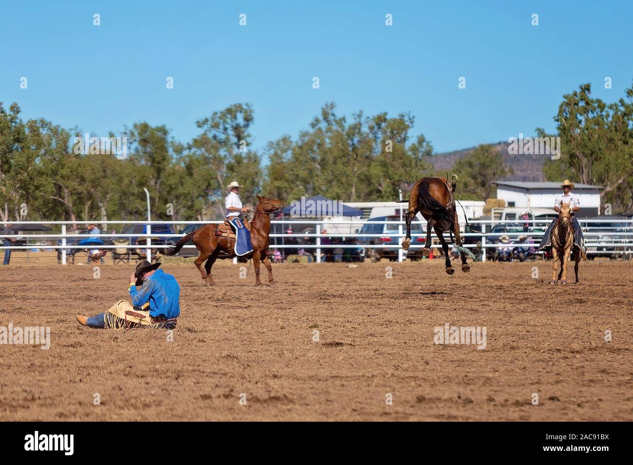 Cowboy riding a bucking bronco horse in a competition at a country ...