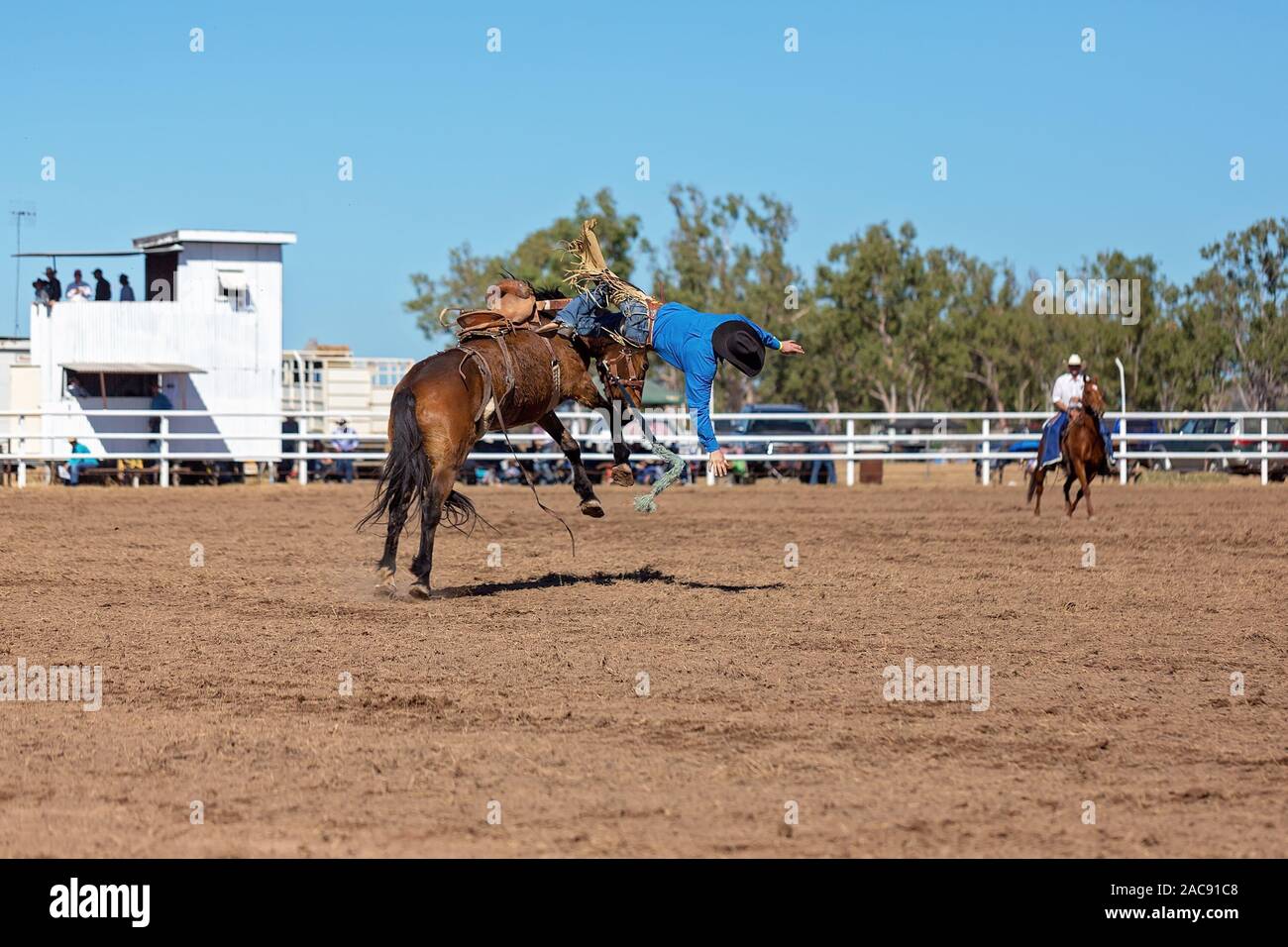 Cowboy riding a bucking bronco horse in a competition at a country ...