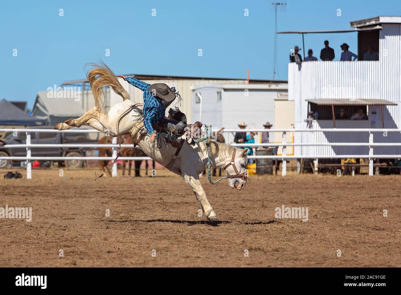 Cowboy riding a bucking bronco horse in a competition at a country ...
