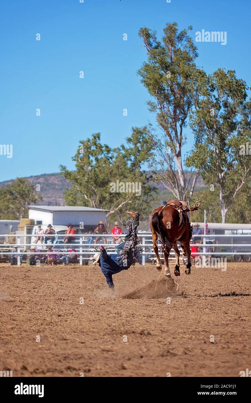 Cowboy riding a bucking bronco horse in a competition at a country ...
