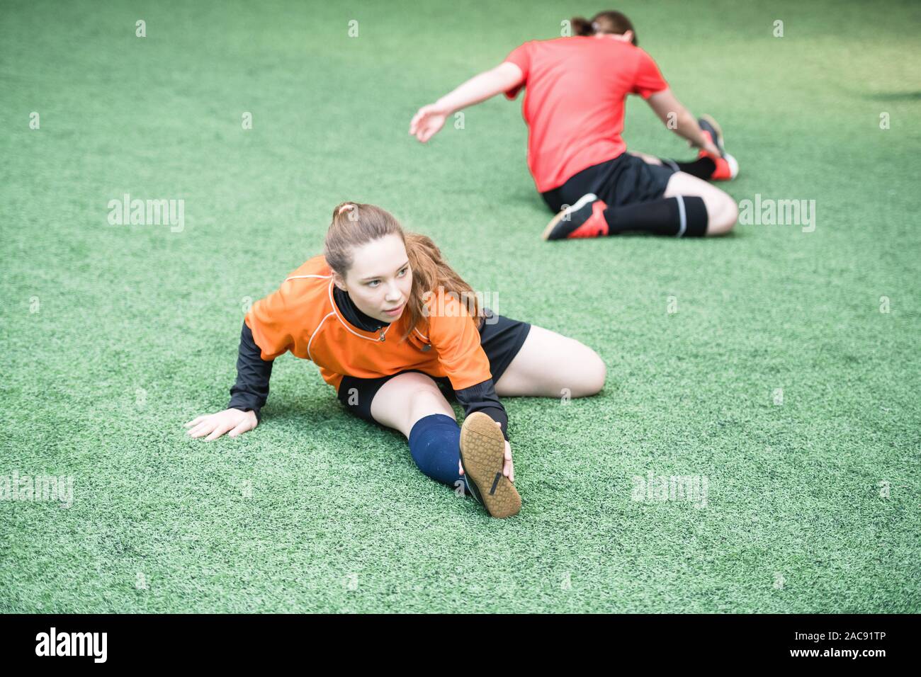 Small group of active female footballers in sports uniform doing ...