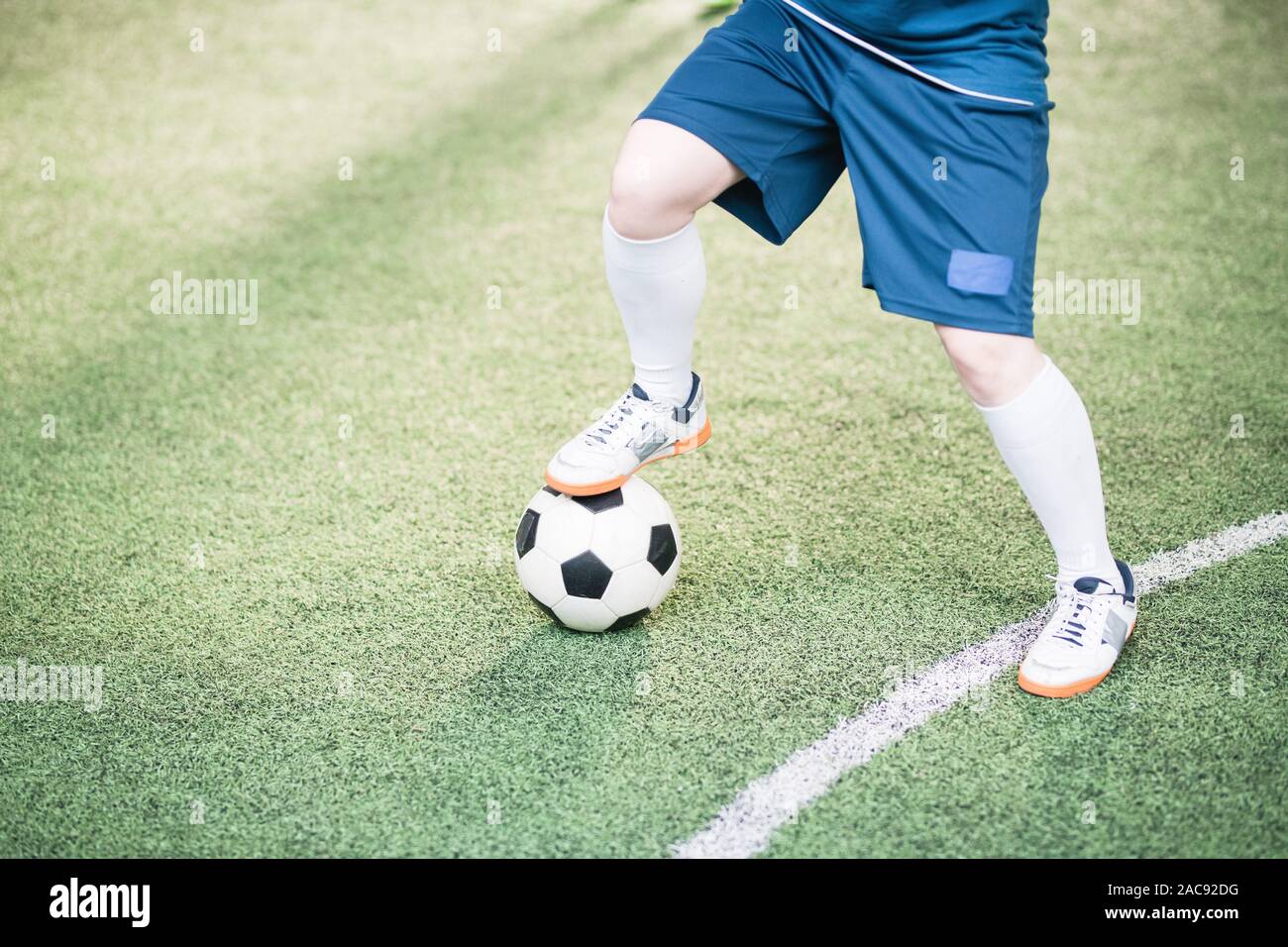 Legs of young active female player in blue uniform keeping right foot ...