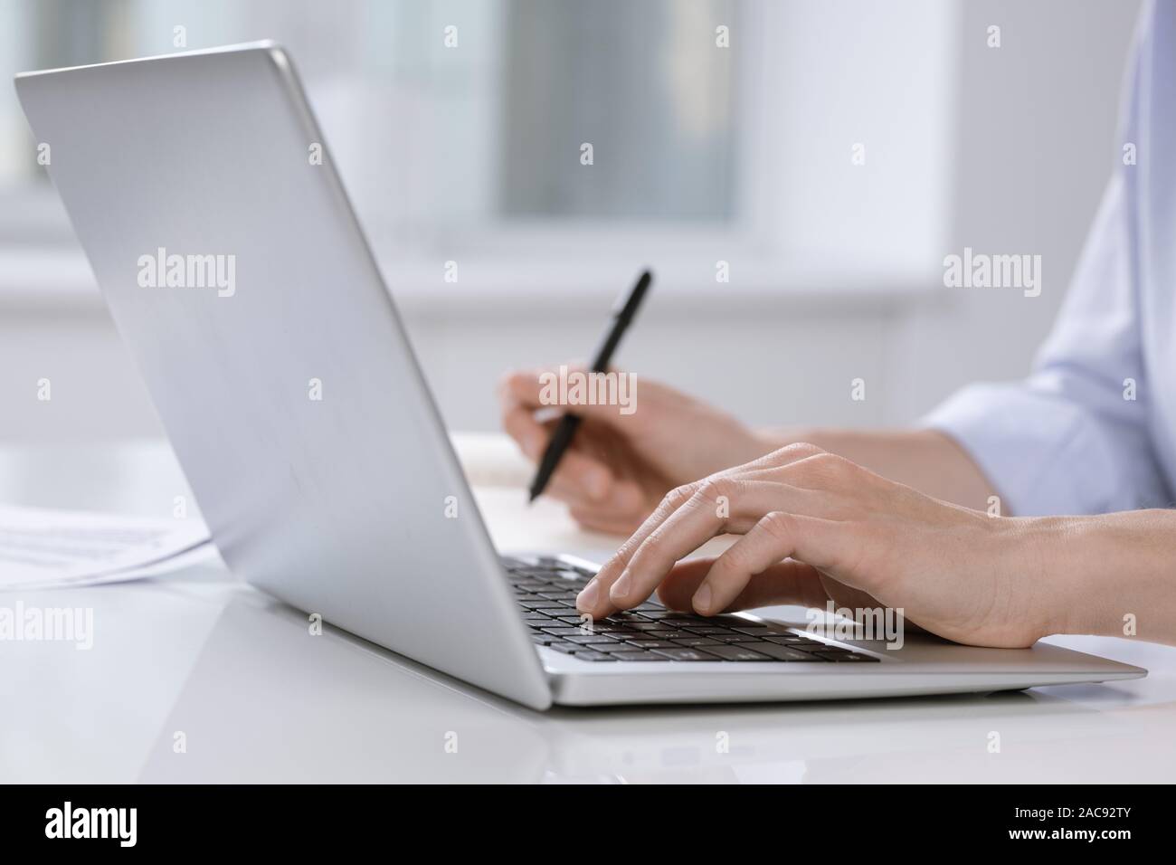 Hand of female employee pushing buttons of laptop keypad while sitting ...
