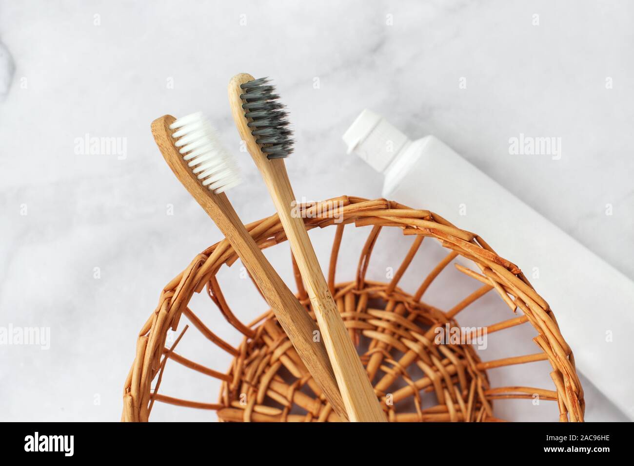 Set of eco-friendly toothbrushes, toothpaste in straw basket on marble ...