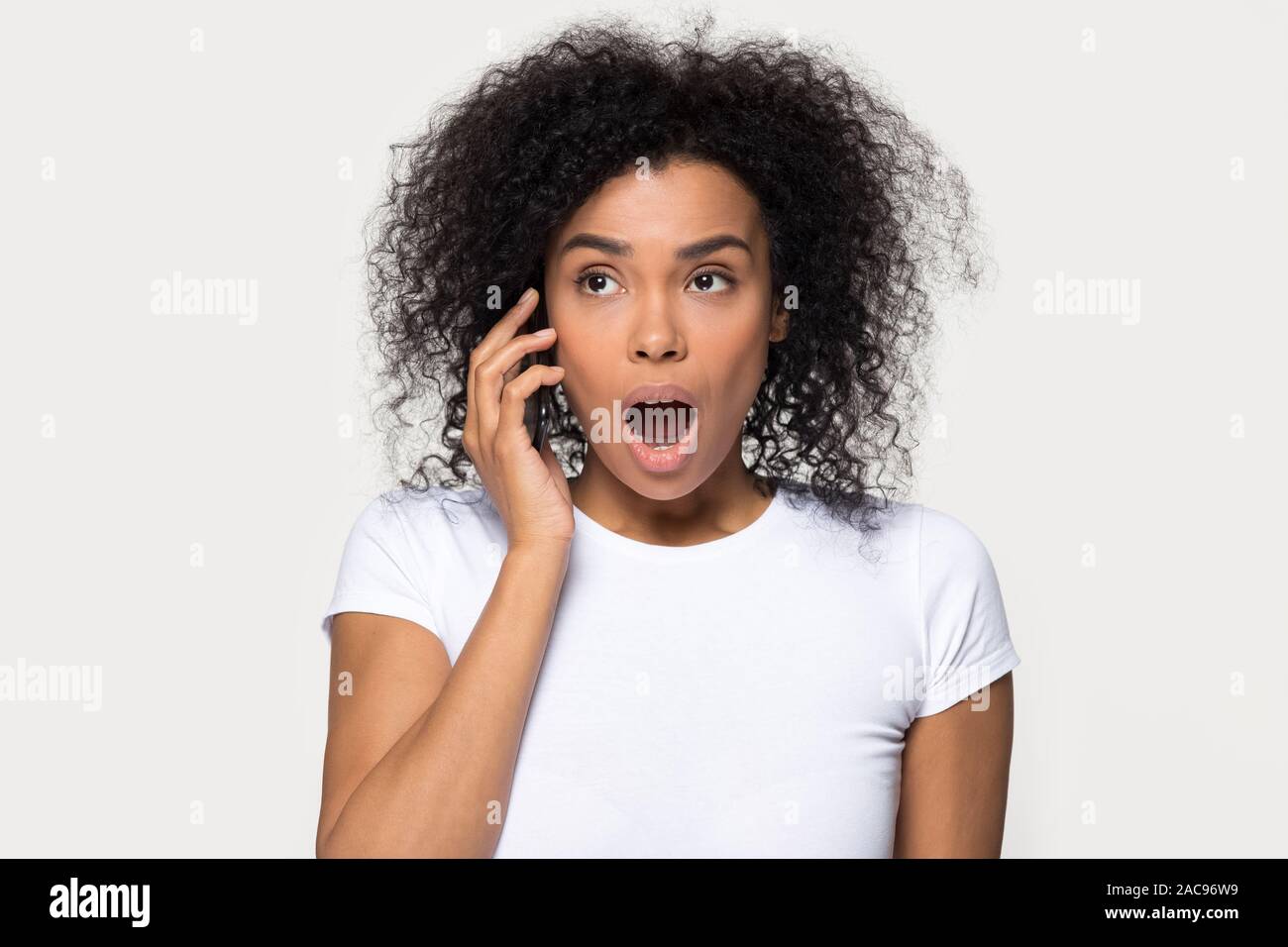 Shocked African American woman talking on phone, hearing unexpected ...