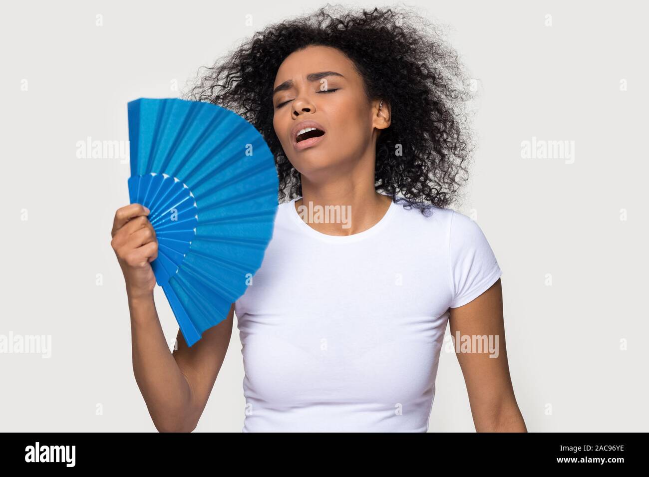 Tired African American woman suffering from heat, waving fan Stock ...