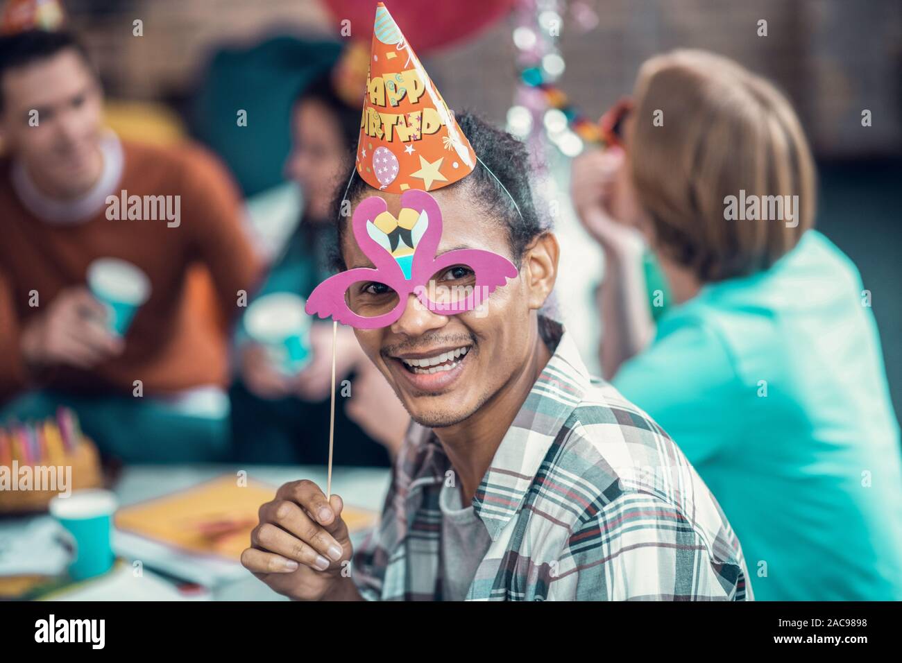 Party with friends. Dark-skinned birthday man holding glass while ...