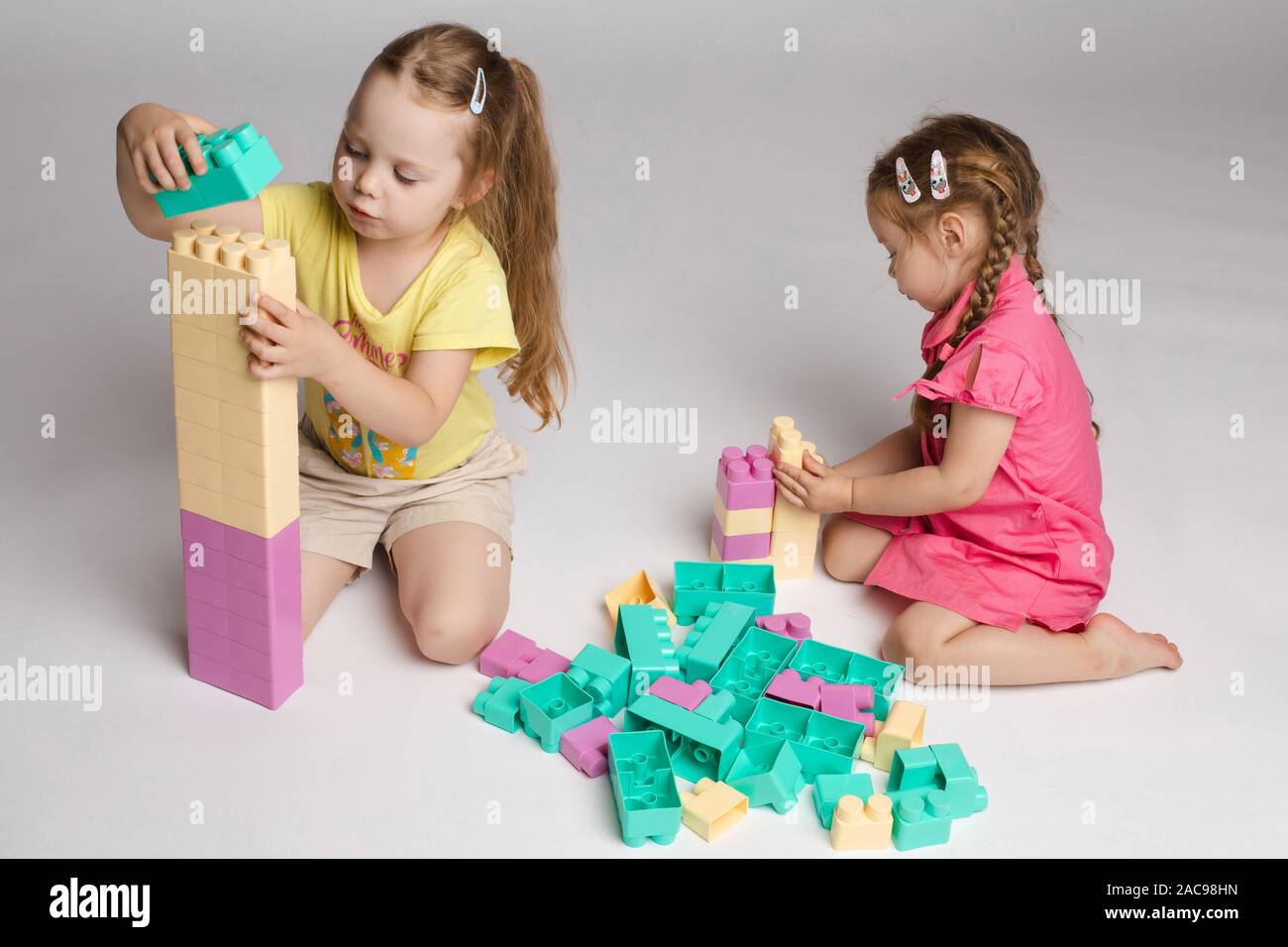 Two girls sitting on floor and playing with building blocks Stock Photo ...