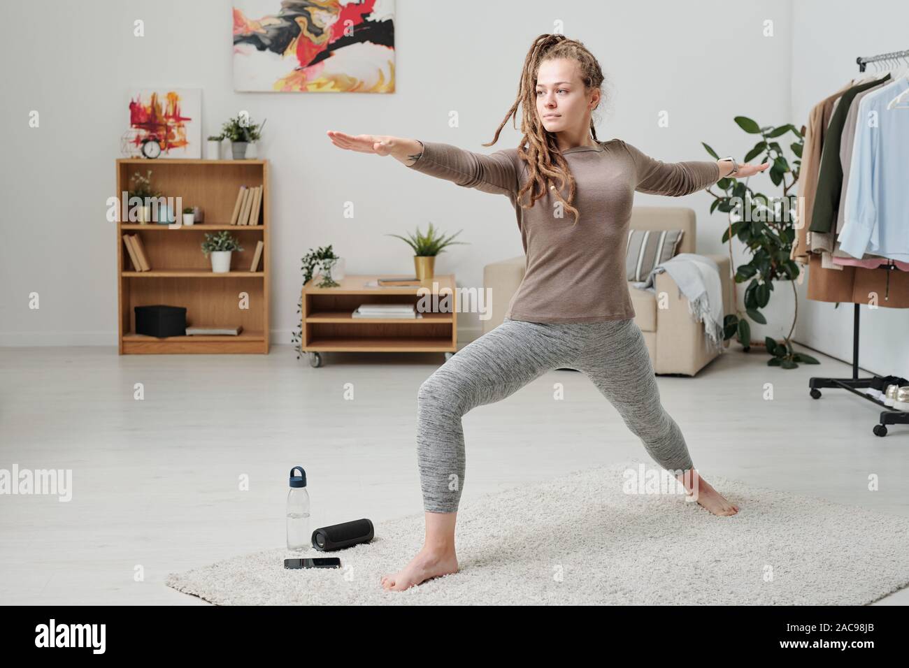 Pretty girl in activewear stretching legs and arms while working out on ...