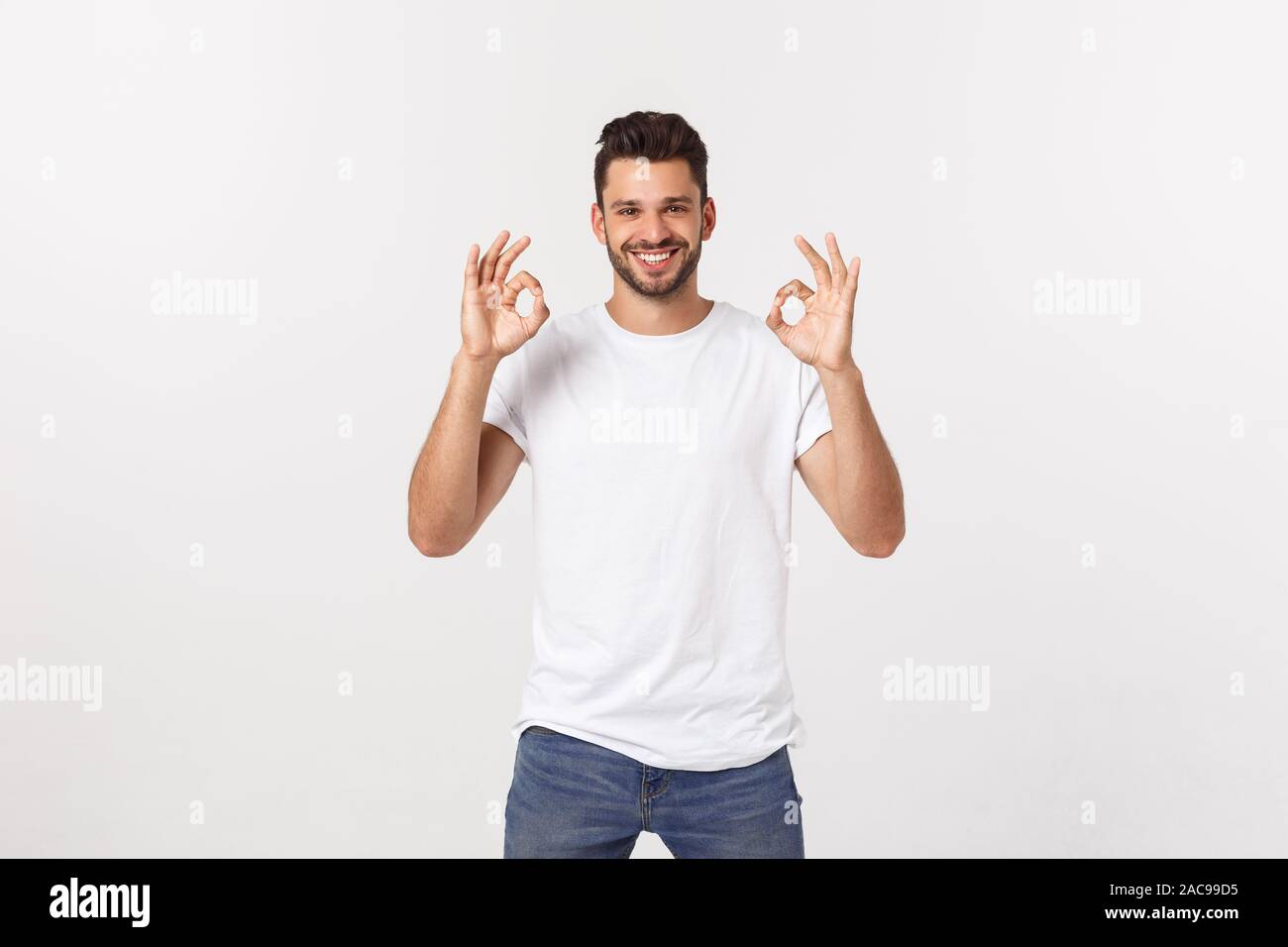 Satisfied young man showing okay sign isolated on white background ...