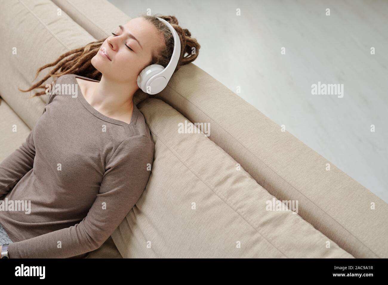 Cute female enjoying music for relax while sitting on comfortable couch ...