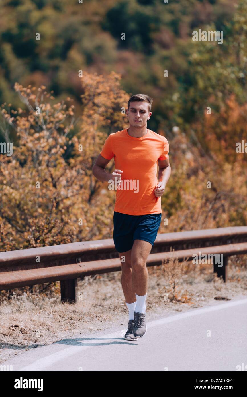Muscular fit sport model sprinter exercising sprint on mountain road ...