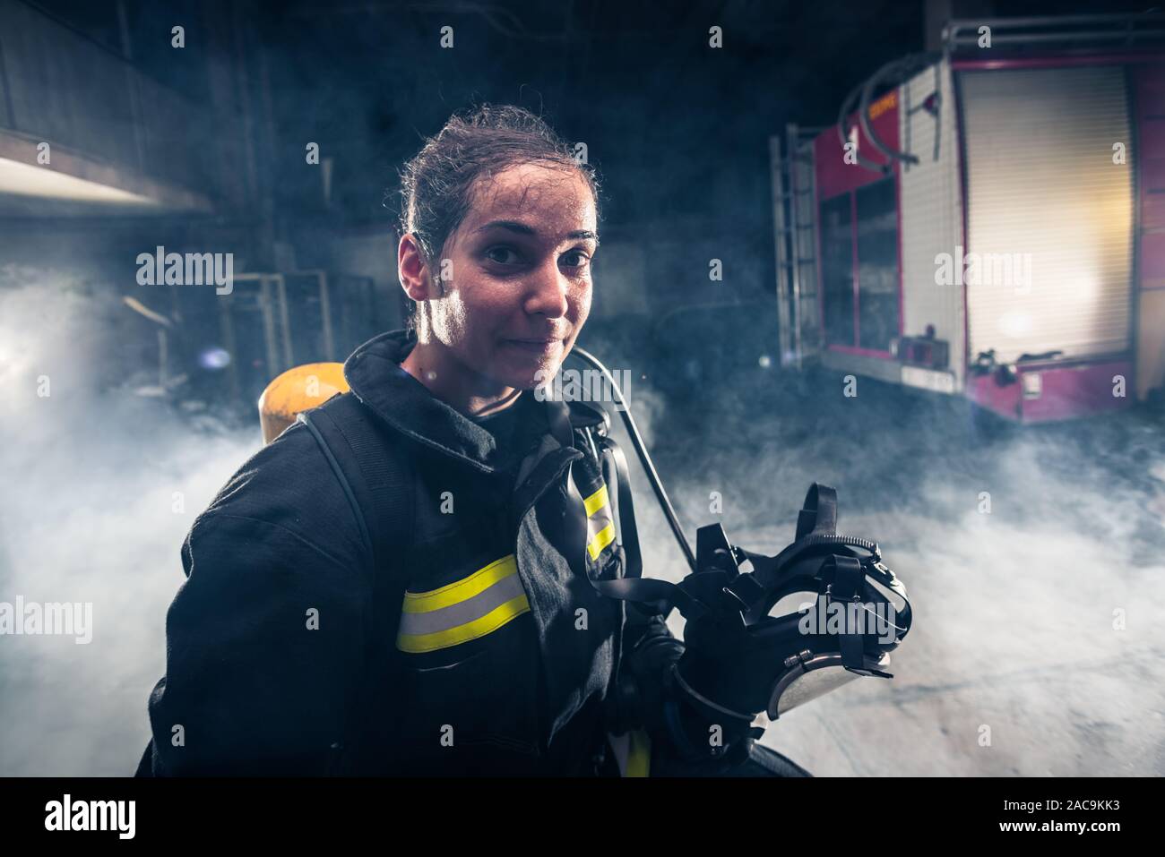 Portrait of a female firefighter while holding an axe and wearing an ...