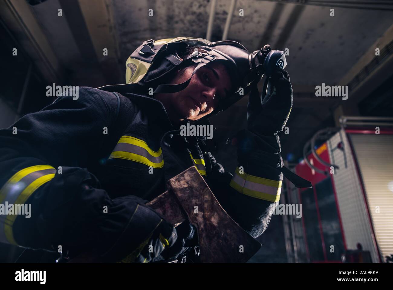 Portrait of a female firefighter while holding an axe and wearing an ...