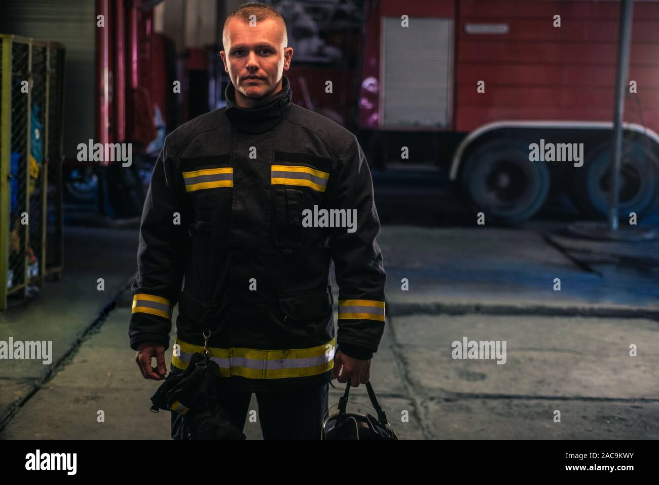 Portrait of young fireman standing inside the fire station Stock Photo ...