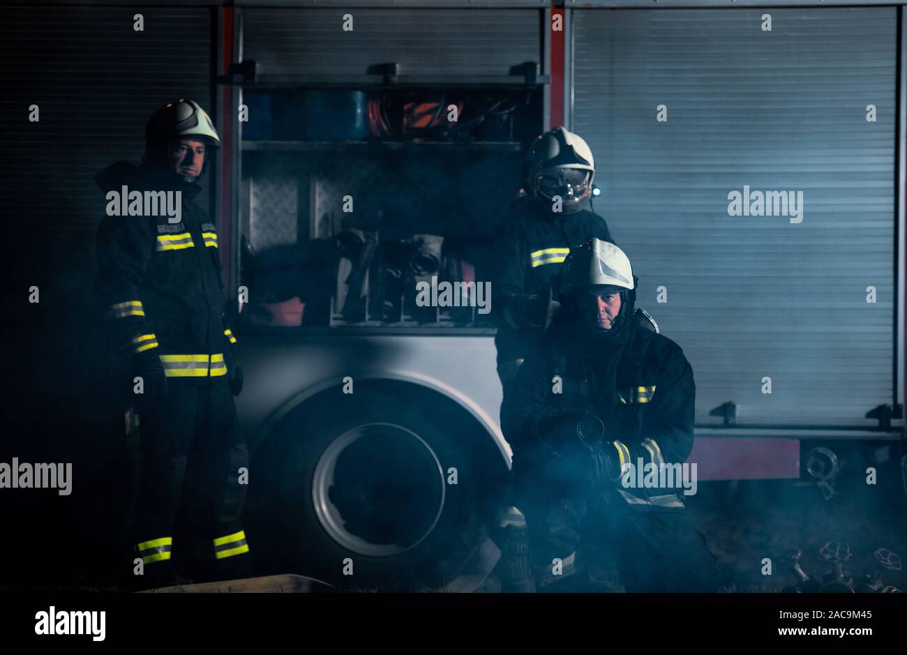 Firemen using fire hose that shoots foam and water during an emergency ...