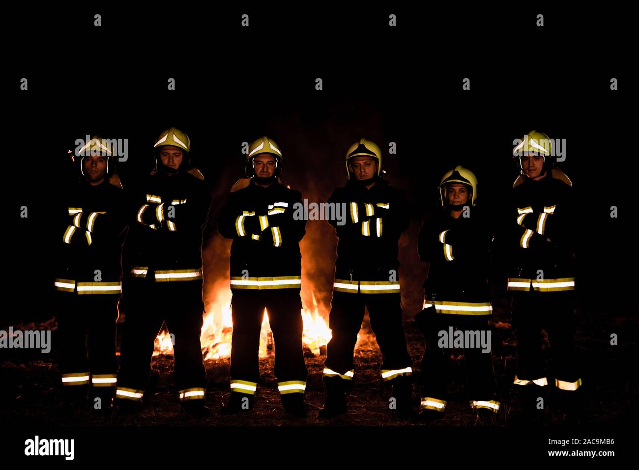 Fireman team in full equipment with helmets and gas masks fighting a ...