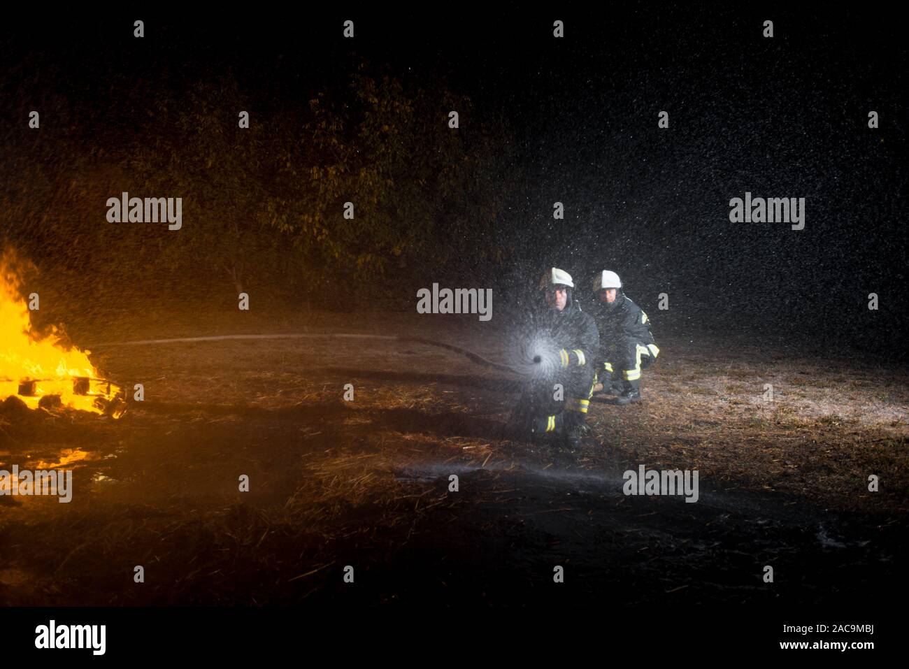 Firefighting group in action battling flames during night time Stock ...