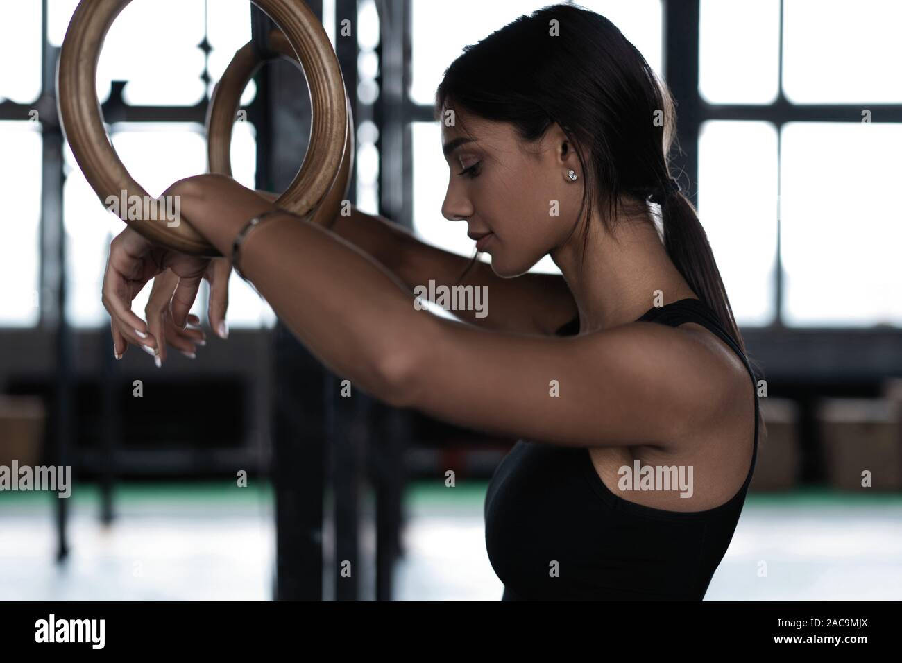 Exercising woman holding gymnast rings and looking away. Female taking ...