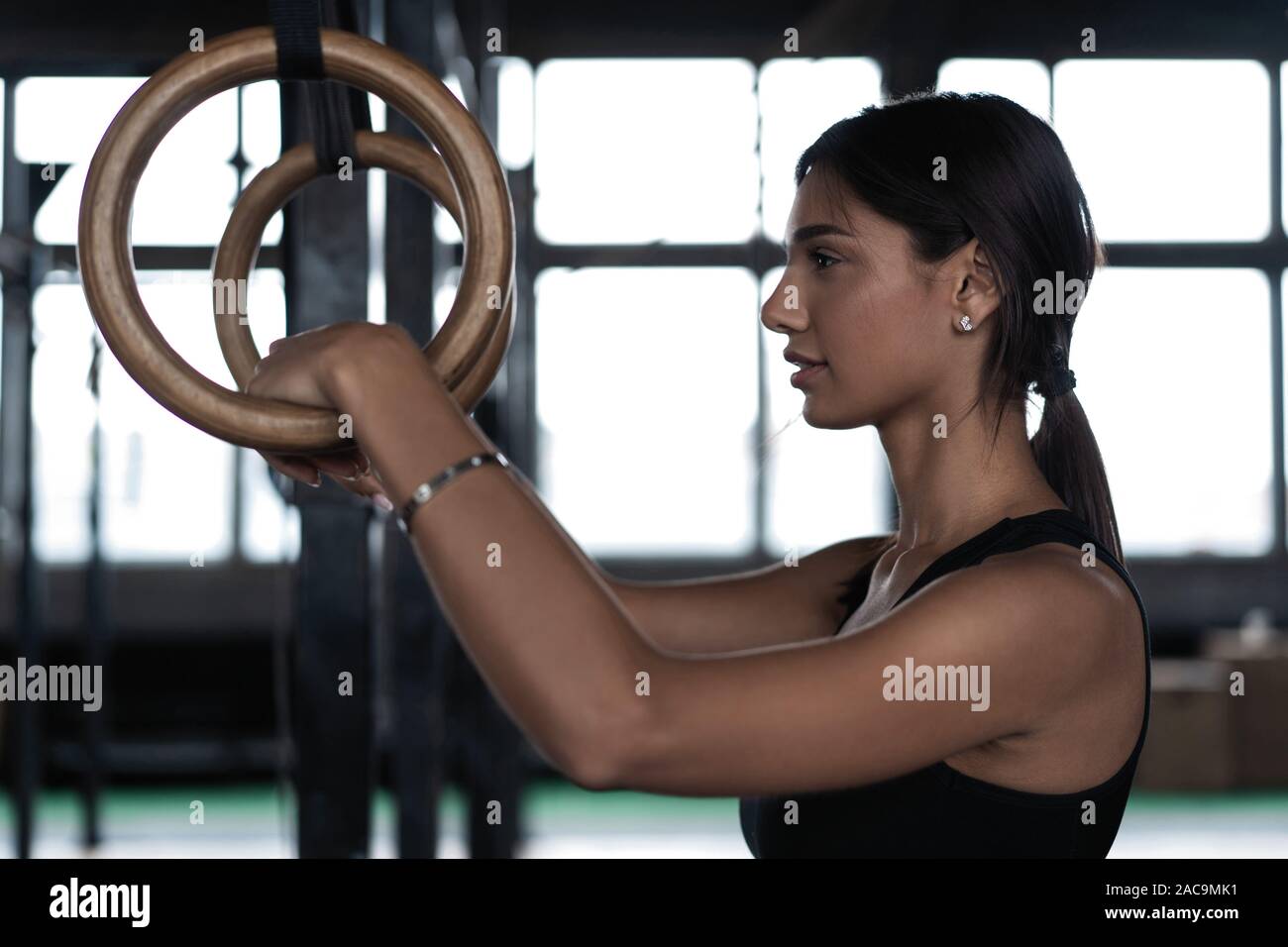 Exercising woman holding gymnast rings and looking away. Female taking ...