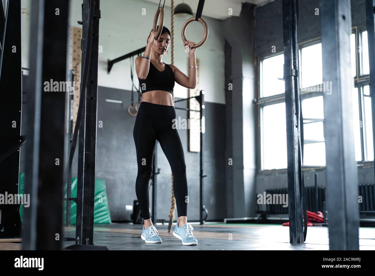 Exercising woman holding gymnast rings and looking away. Female taking ...