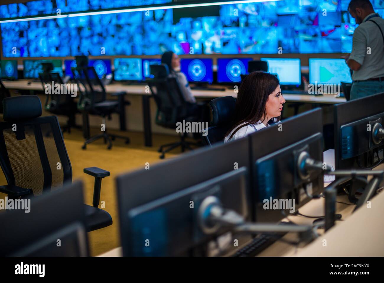 Female security guard sitting and monitoring modern CCTV cameras in ...