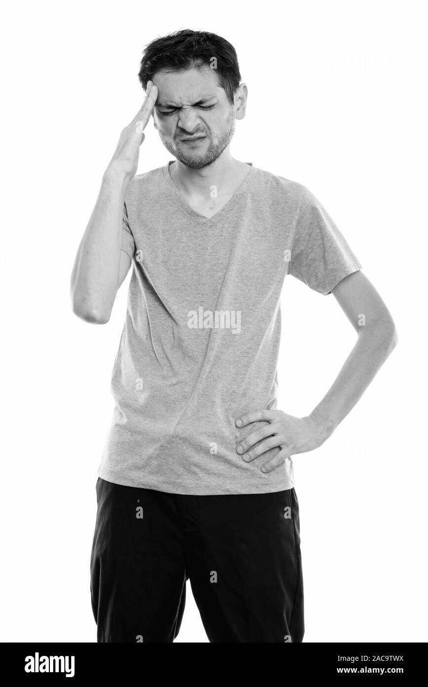 Studio shot of stressed young man standing while having headache Stock ...
